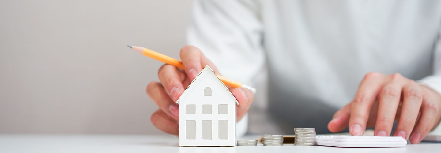 A man touching a little white house, on a table and besides there are ...
