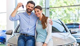 A woman and a man in front of a car, the man is holding a key.